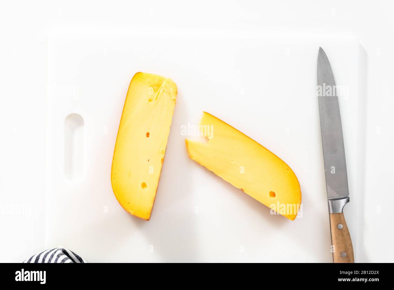 Large slice of smoked gouda cheese on a white cutting board Stock Photo ...