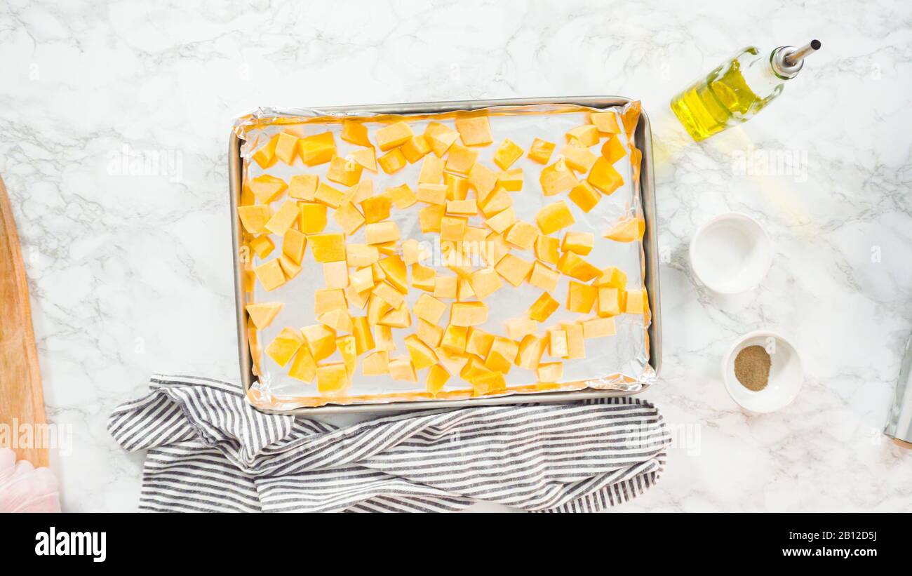 Seasoning butternut squash with oil, salt, and pepper for roasting in ...