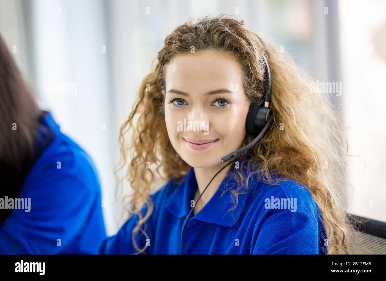 Smiling female customer support operator with headset working in office Stock Photo - Alamy