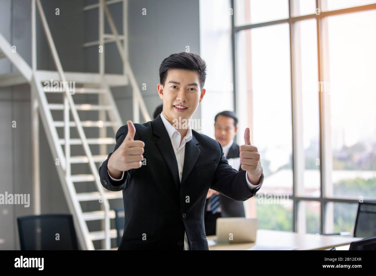 Asian young handsome business man standing against people sitting at ...
