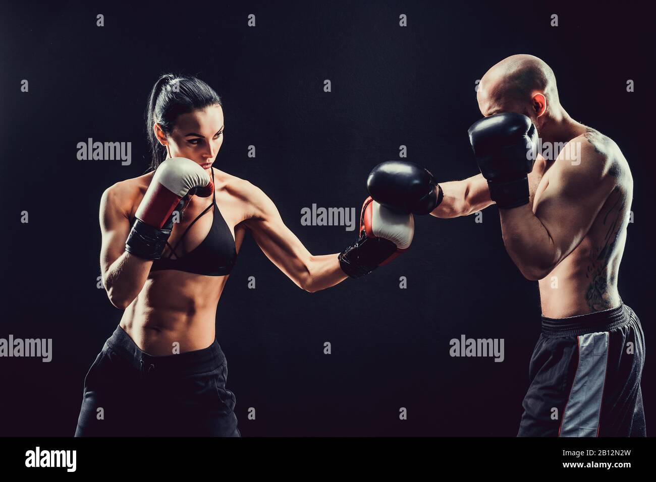 Shirtless Woman exercising with trainer at boxing and self defense ...