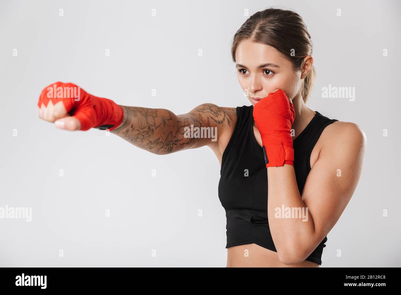 Image of pretty woman wearing sportswear training in boxing hand wraps ...