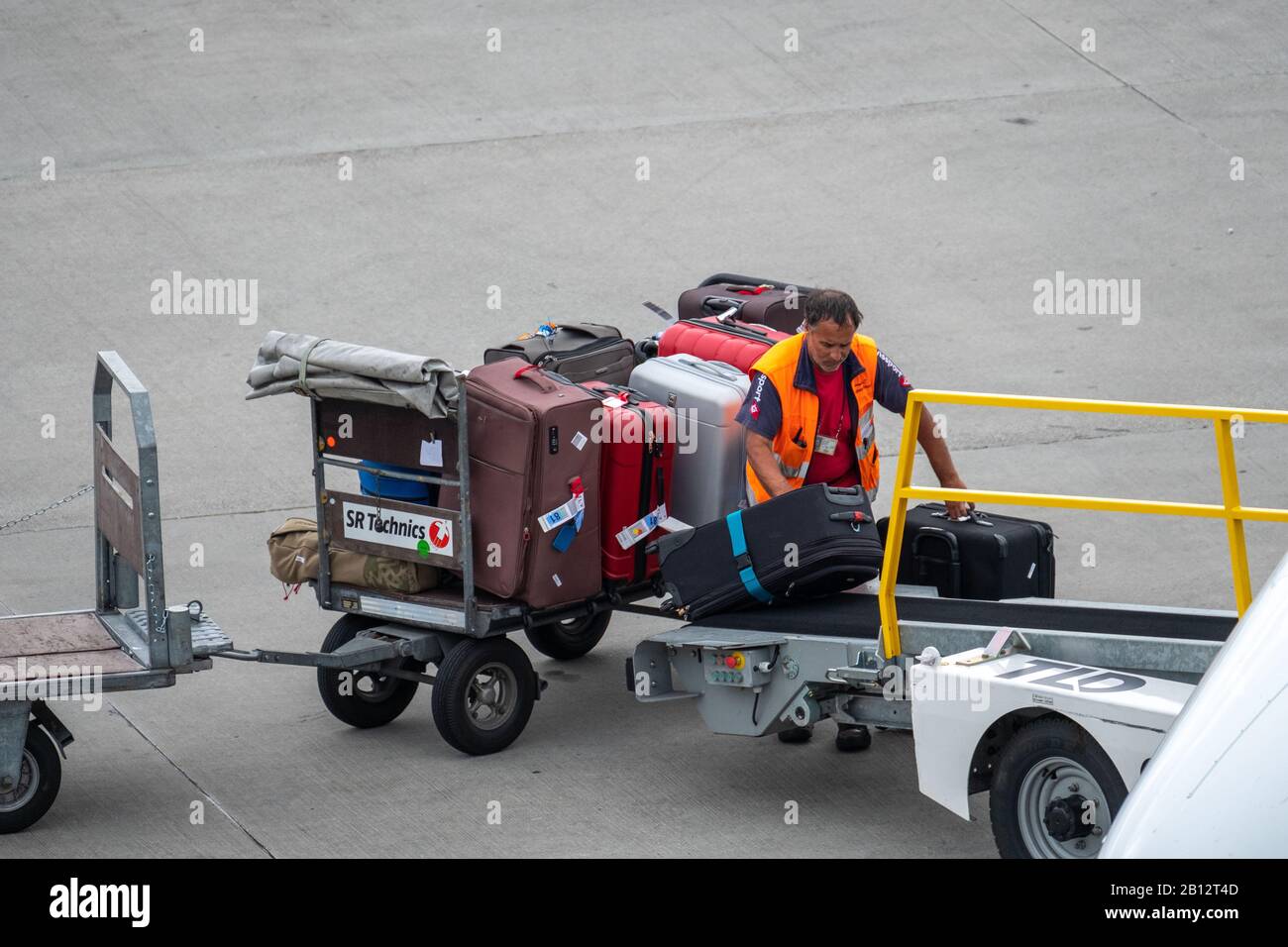 Airport worker loads luggage on a loader conveyor Stock Photo - Alamy
