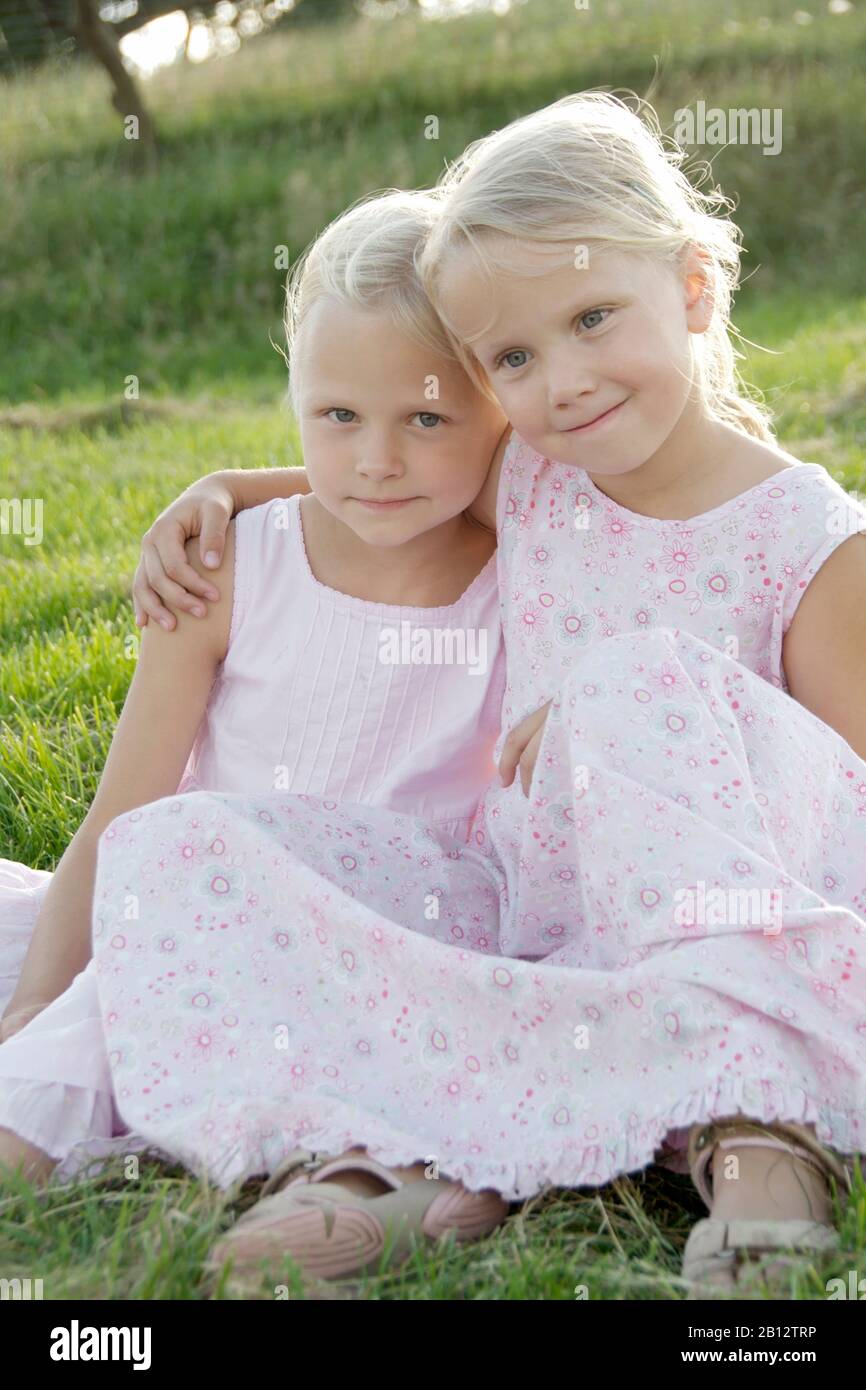 Portrait of two girl friends putting their arms around their shoulders ...