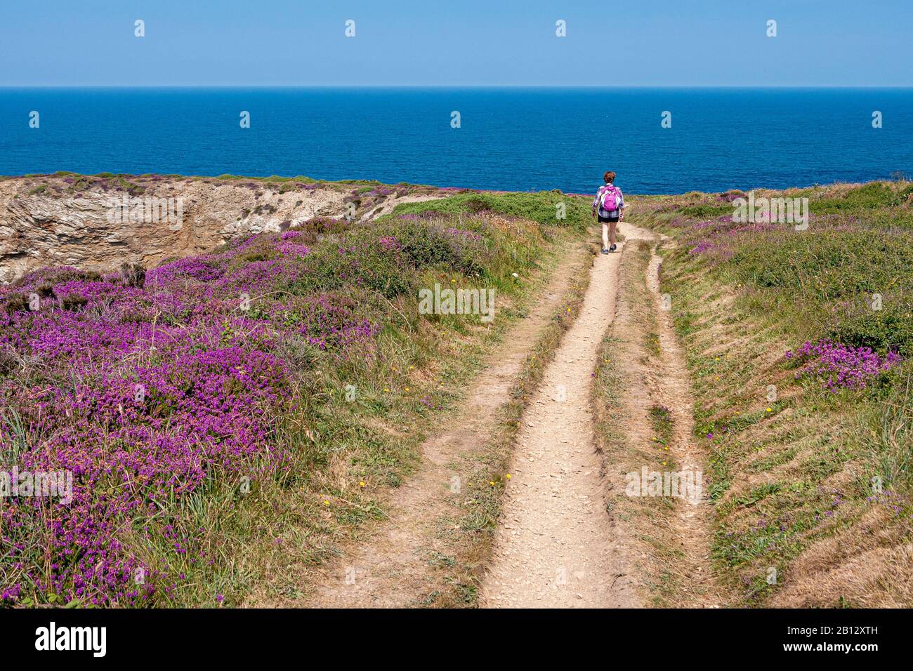 A walker passes above Gooden Heane Cove heading twards Porthtowan on ...