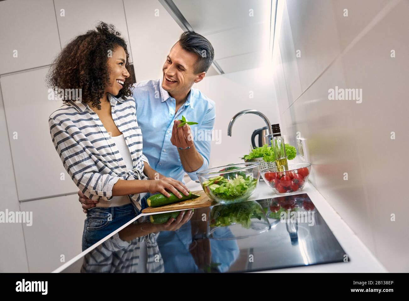 Romantic Date. Young multiethnic couple standing at kitchen cooking ...