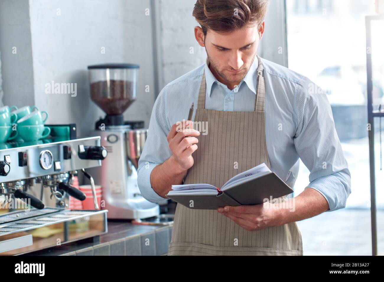Coffee Passion. Young barista at coffee shop reading instructions at ...