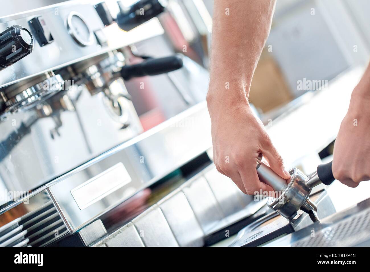 Young adult barista working in cafe, using tamper tool to making coffee ...