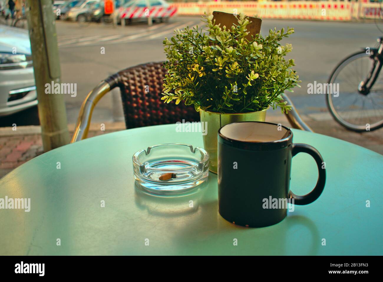 Coffee mug ashtray and fake plant on a teal table in a Schoneberg Cafe ...