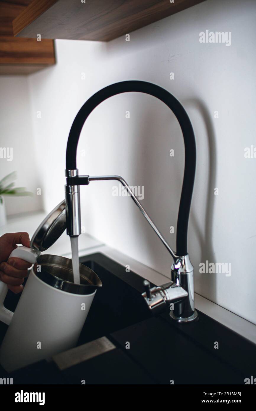 Vertical picture of man's hand holding electric kettle with opened top ...