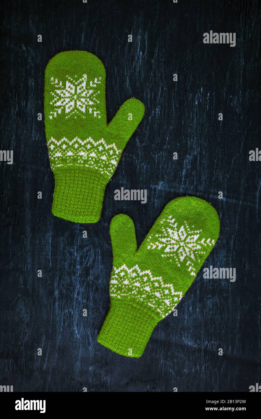 a pair of blue-green knitted mittens on a dark blue-green-brown wooden ...