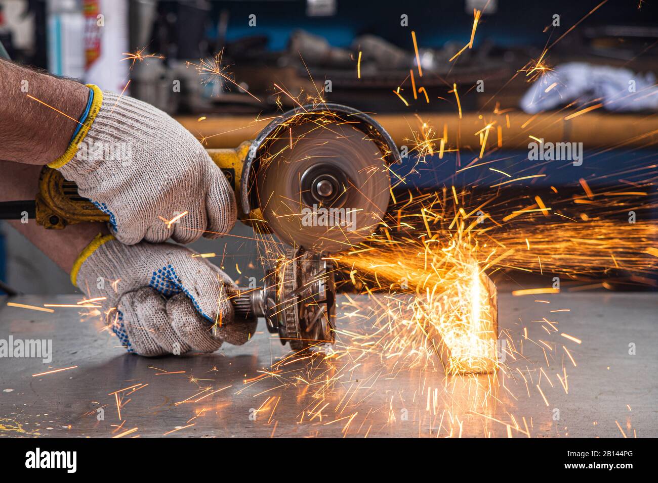 A young man welder grinder metal an angle grinder in the workshop ...