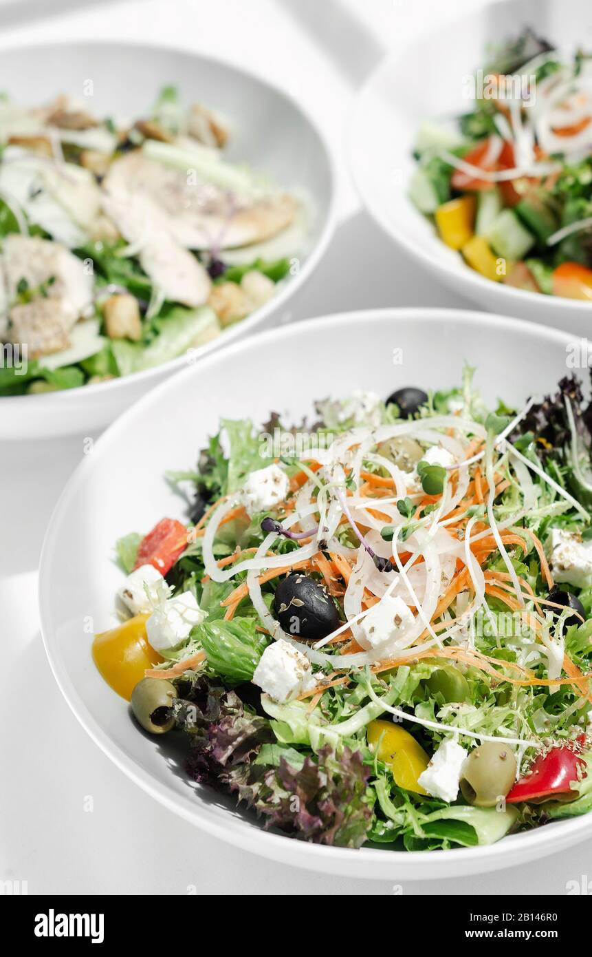 mixed fresh organic salads in bowls on white restaurant table Stock ...