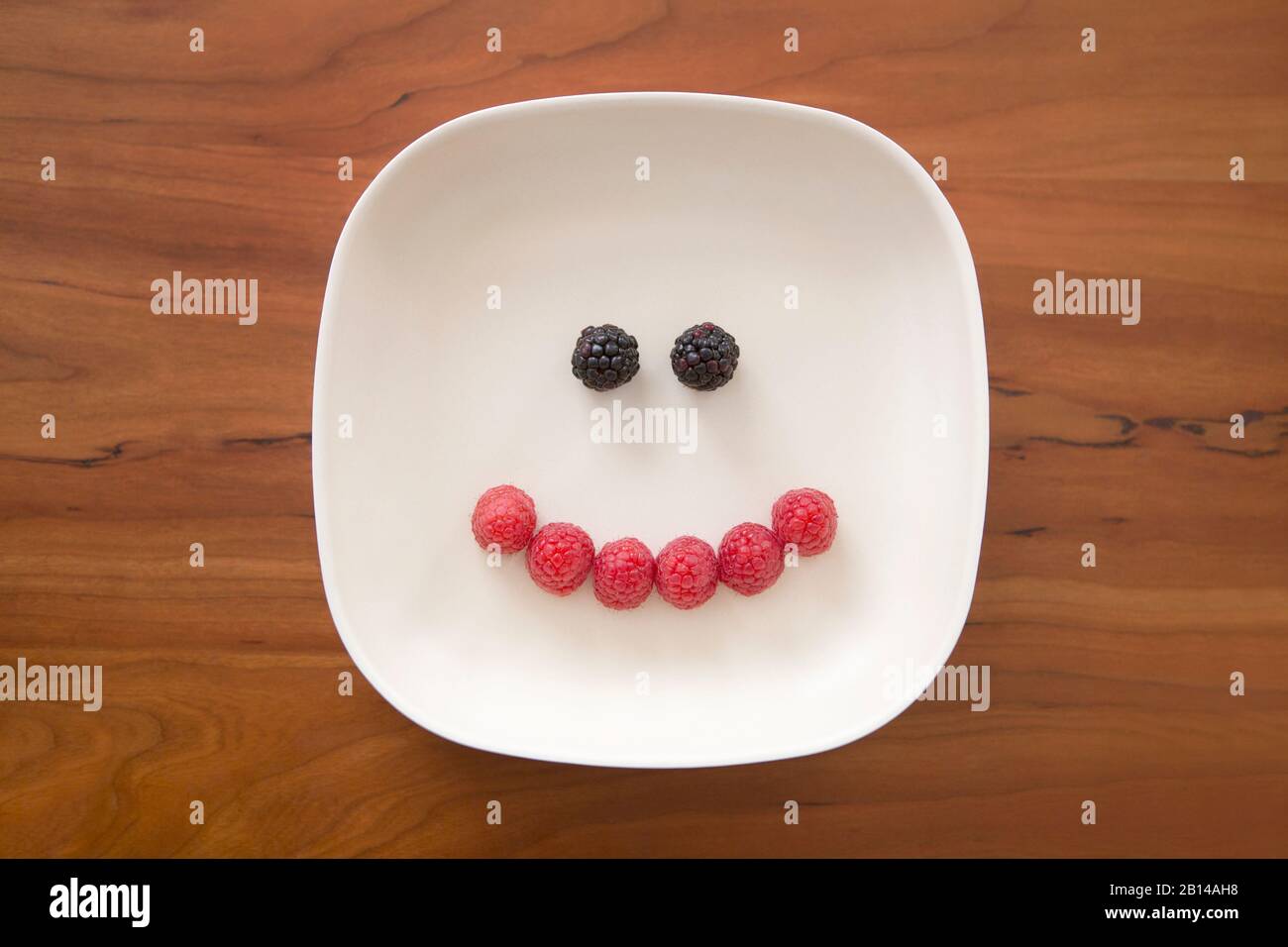 blackberry and raspberry happy face on white plate Stock Photo - Alamy