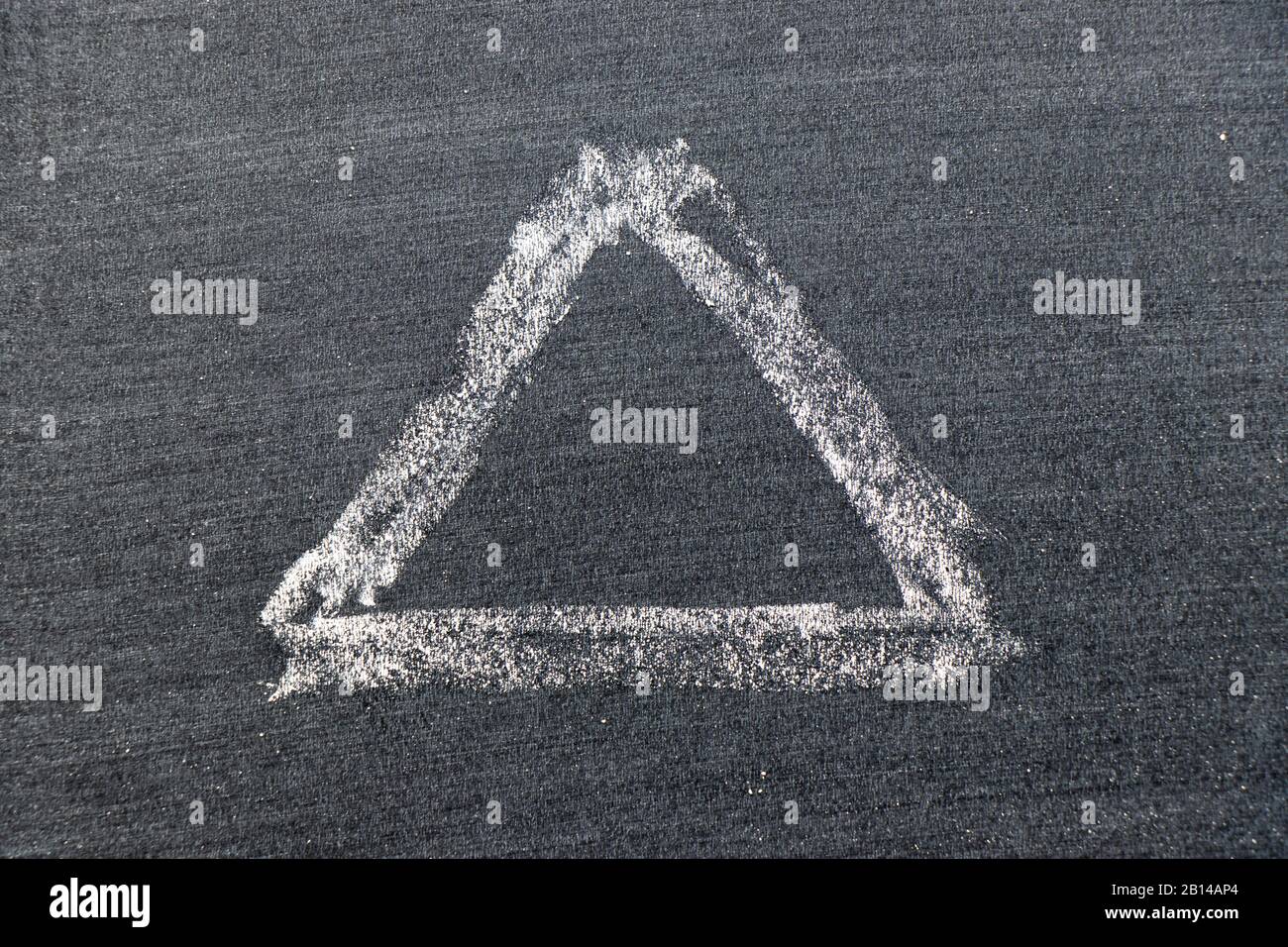 White color chalk hand drawing in triangle shape on black board ...