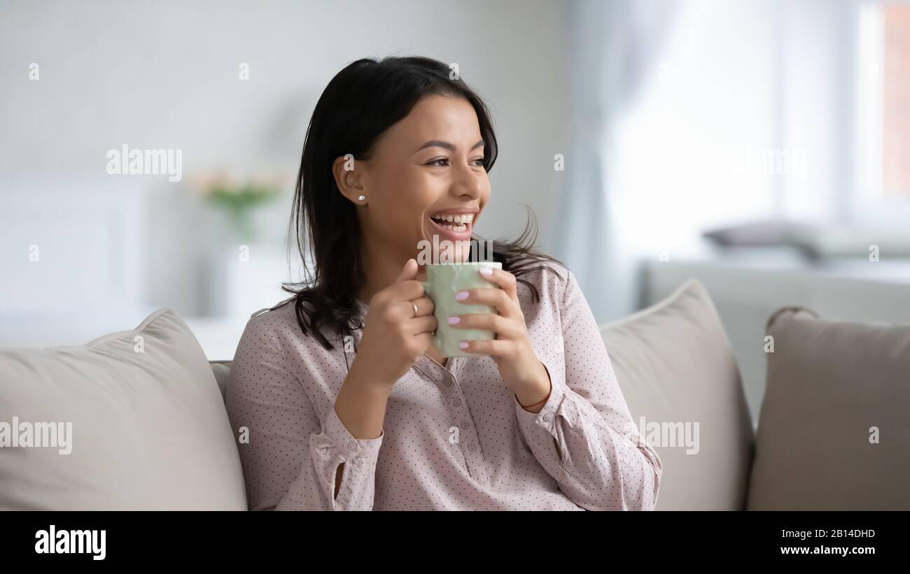 Happy african American woman drink coffee dreaming Stock Photo - Alamy