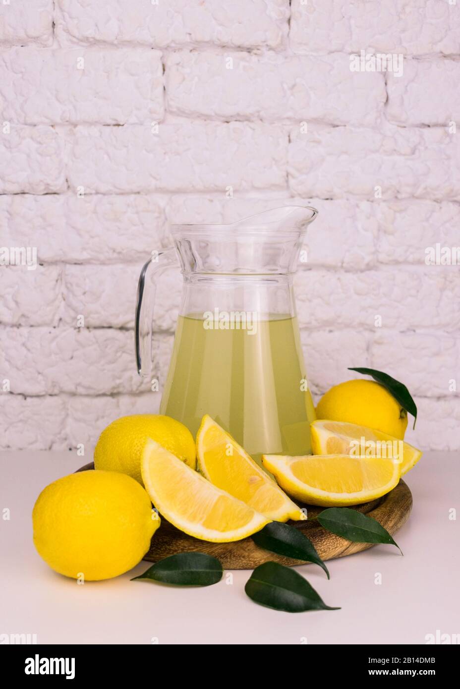 Refreshing lemon drink in a jug and ripe lemons on a white background ...