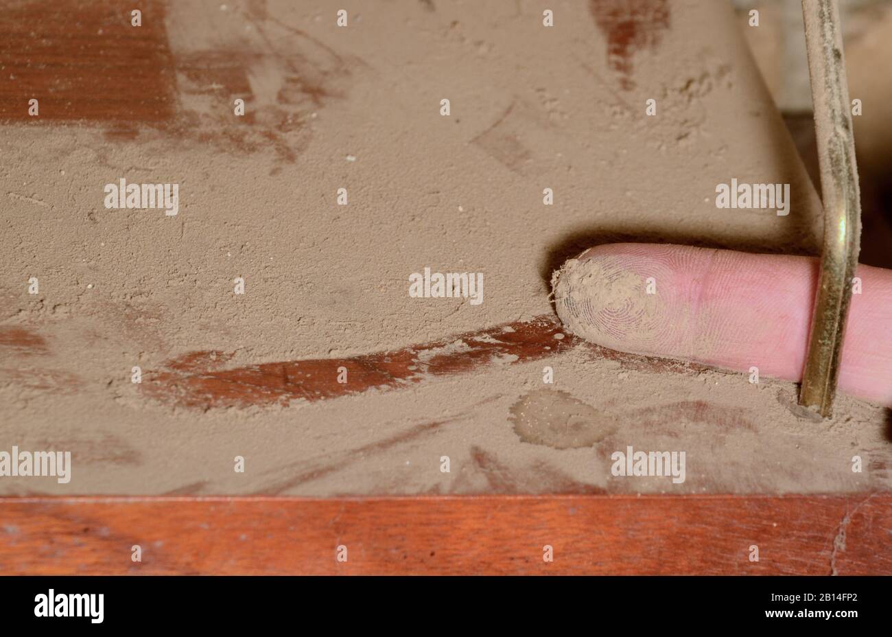 Dust on a shelf, a finger has drawn a line in the dust and shows the ...