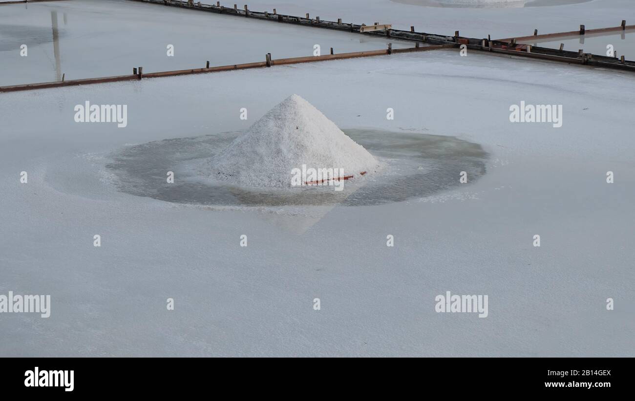 White salt gathered into a pile, surrounded by white salt, at a salt ...