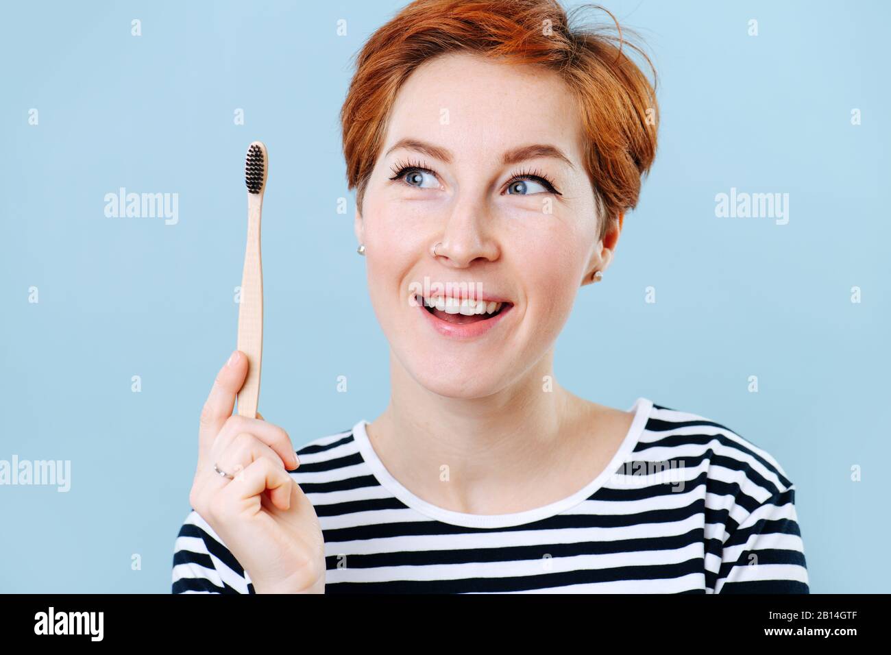 Beautiful woman with short ginger hair with wooden toothbrush in hand ...