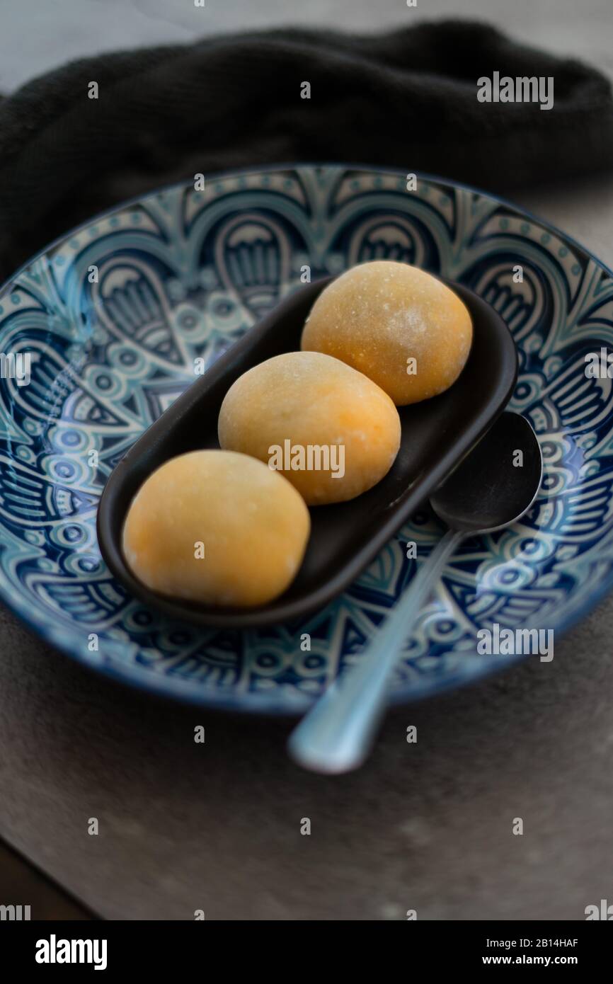 Yellow-colored Japanese Mochi in rice dough and on a pattern blue plate ...