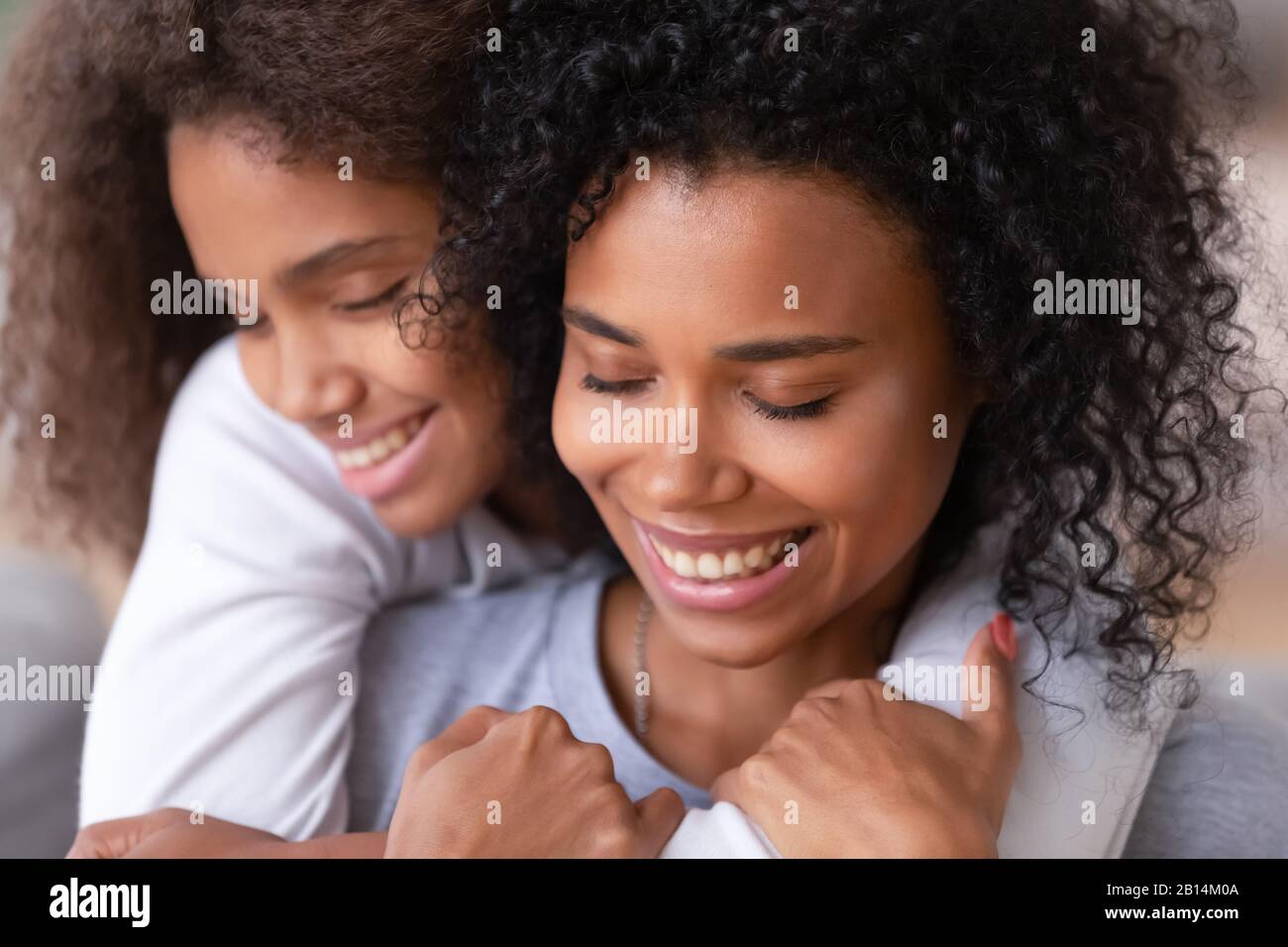 Caring family single mom and african teen daughter embracing cuddling ...