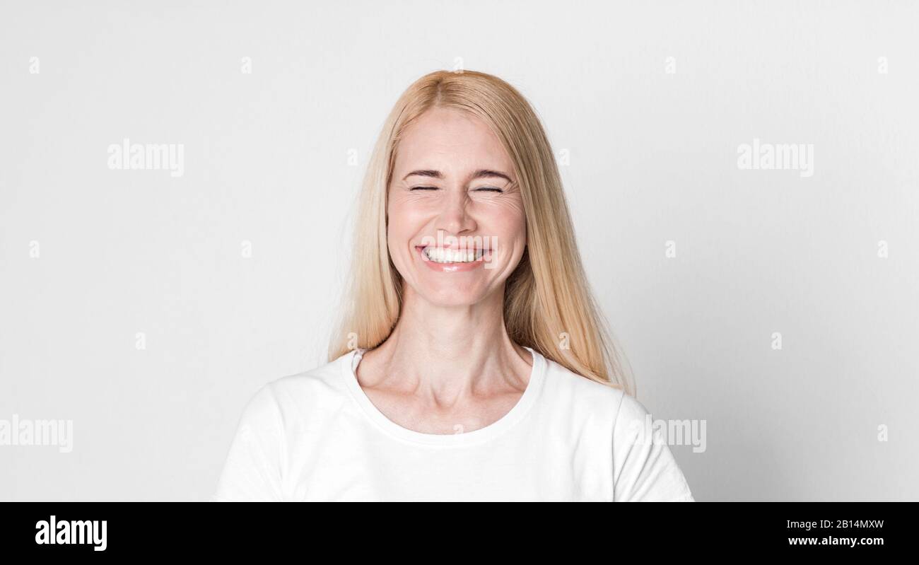 Happy middle-aged woman laughing at grey studio Stock Photo - Alamy