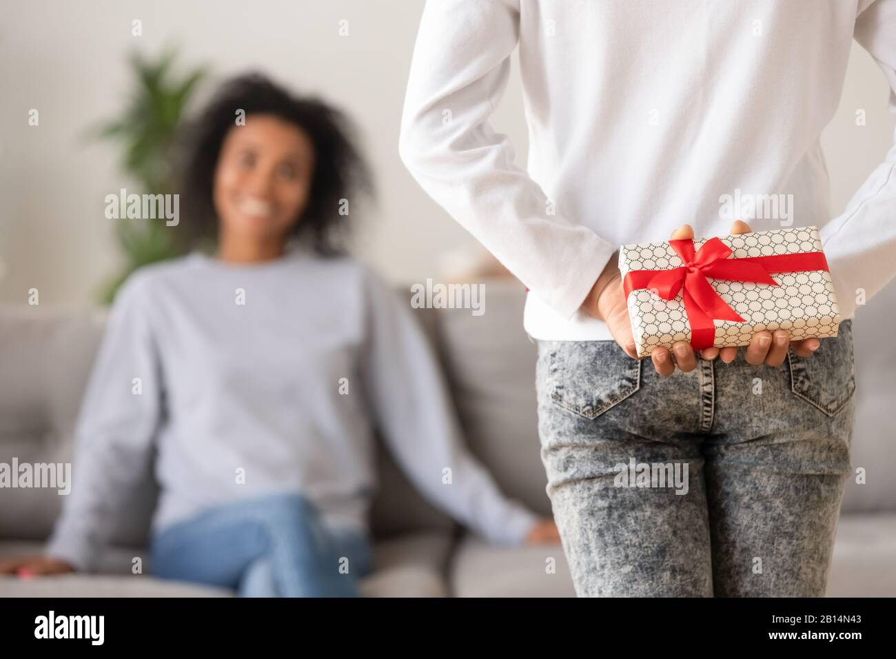 Rear view of teen african daughter holding gift behind back Stock Photo ...