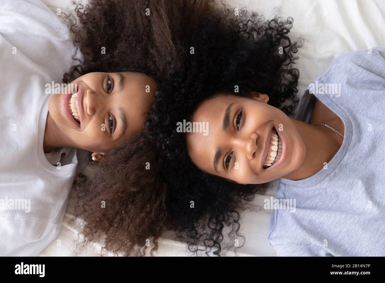 Happy african mother and daughter lying on bed, top view Stock Photo ...