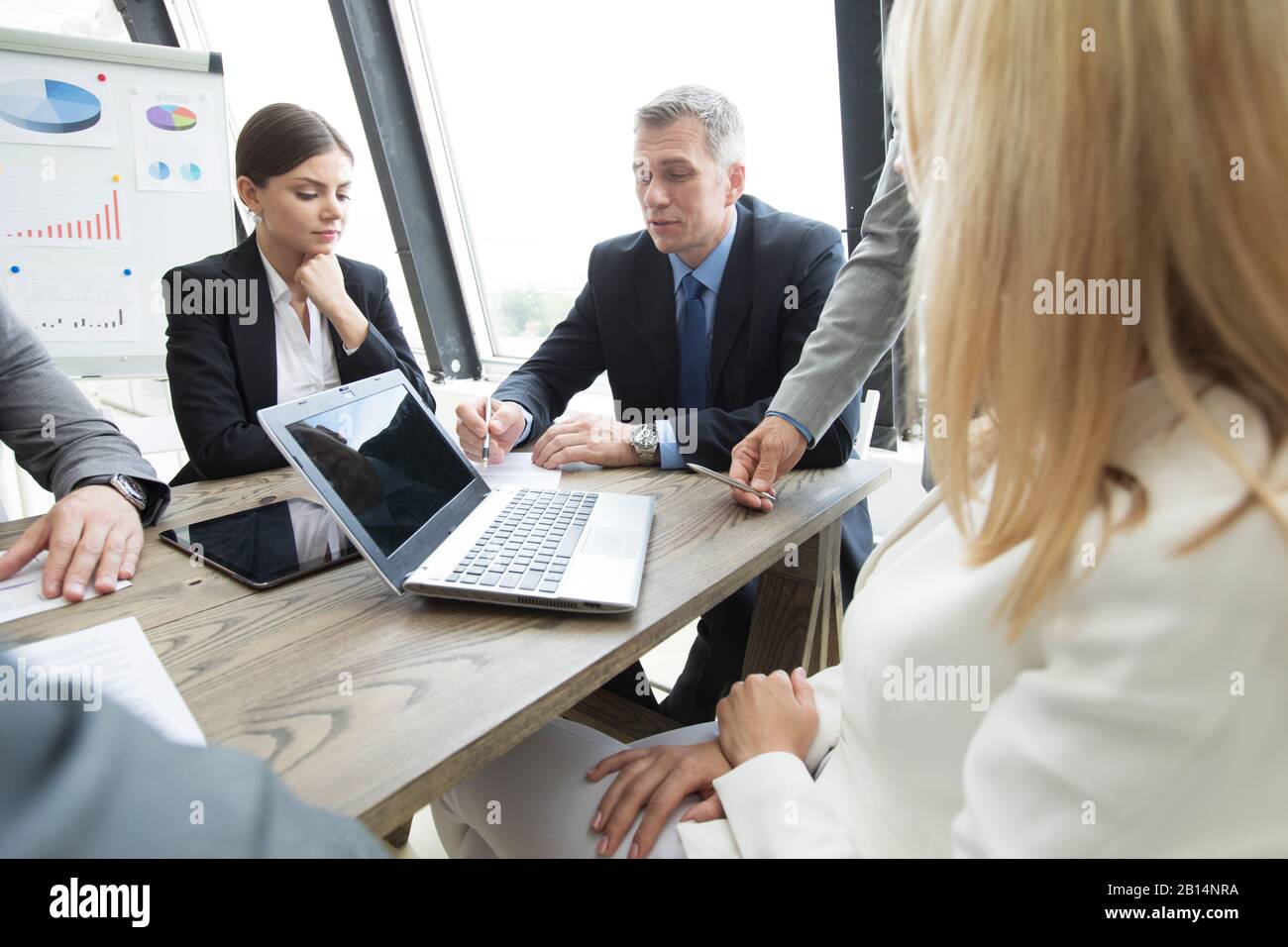 Business people sitting around the desk in a meeting and working with ...