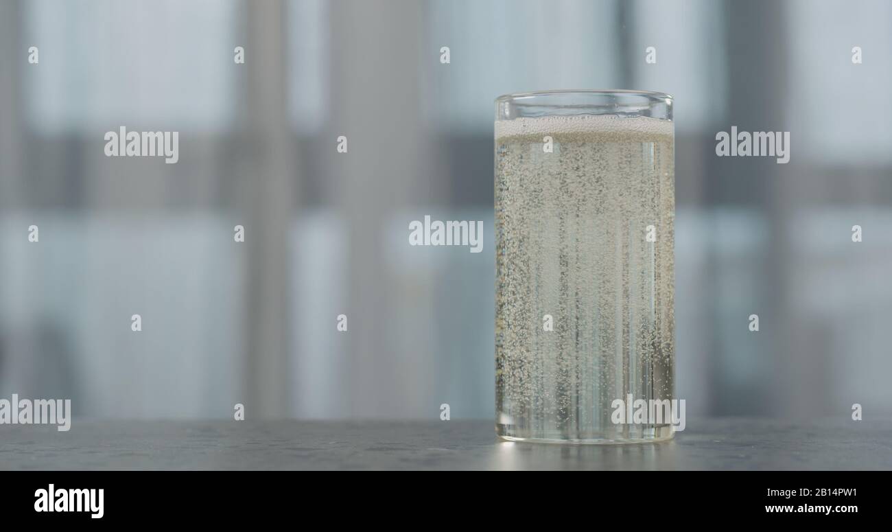pour transparent drink into glass on concrete countertop, wide photo ...