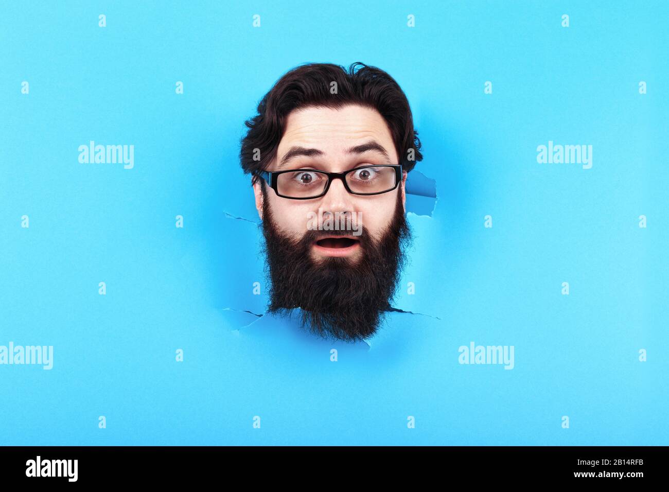 surprised bearded man in hole in the blue background Stock Photo - Alamy