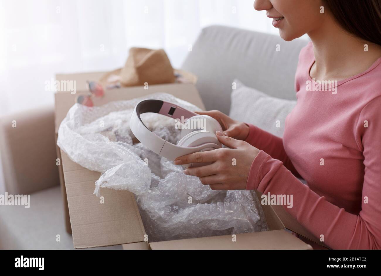 Girl in living room unpacking cardboard box parcel Stock Photo - Alamy