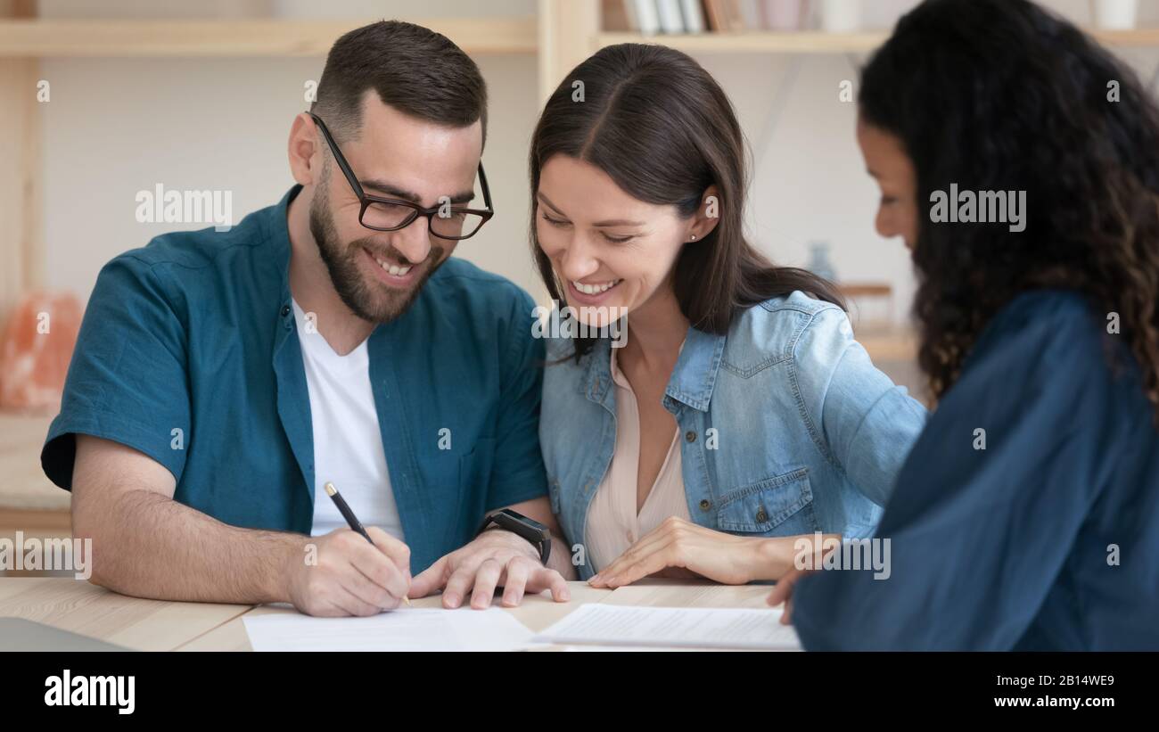 Happy family couple signing contract with agent Stock Photo - Alamy