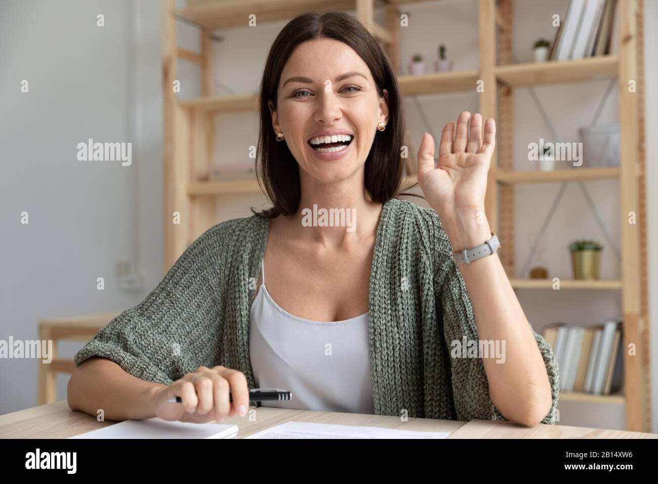 Happy young 30s woman waving hello to camera Stock Photo - Alamy
