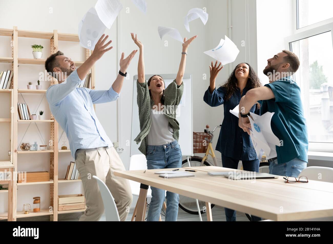 Overjoyed young multiracial business team throwing paper documents in ...