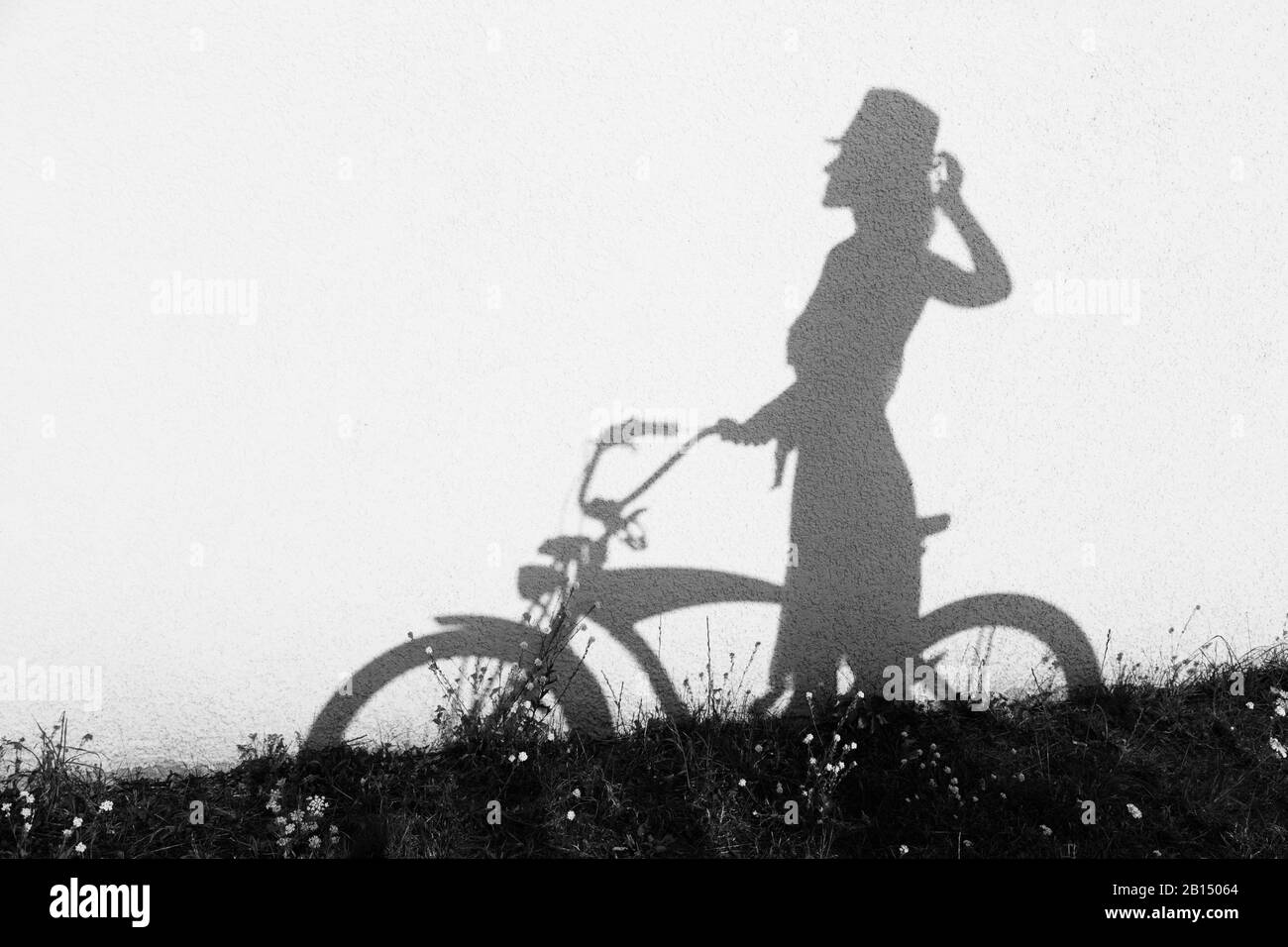 female silhouette with bicycle profile view at concrete wall ...