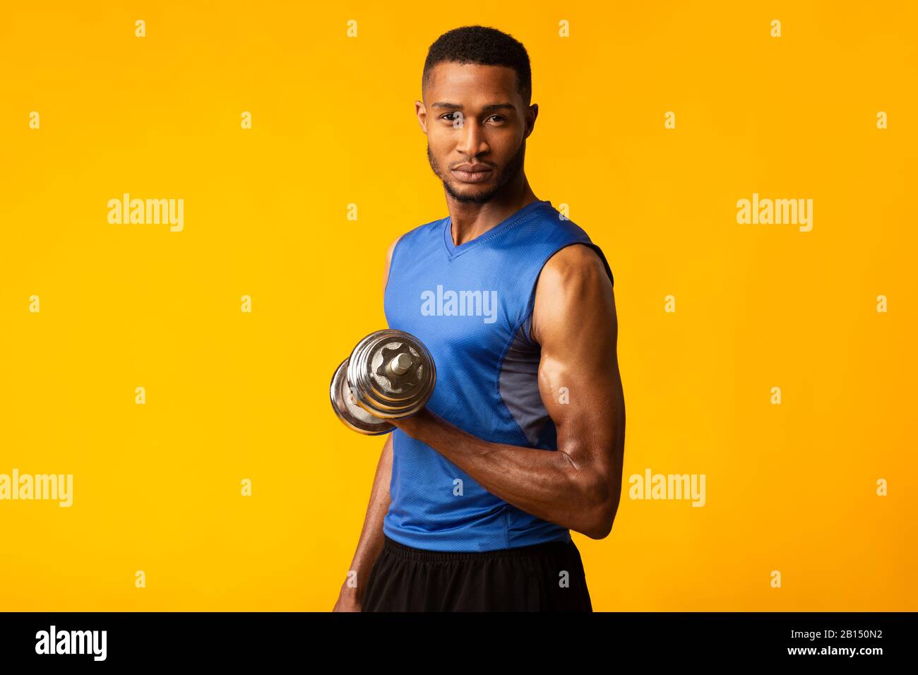 Afro bodybuilder pumping up biceps with dumbbells Stock Photo - Alamy