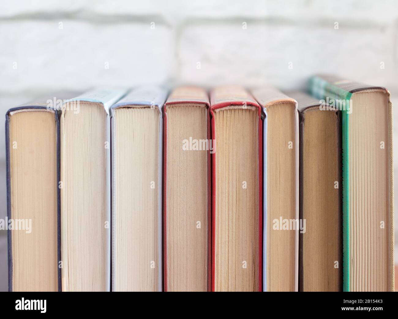 Collection of books of fiction on a light brick background.Books stand ...