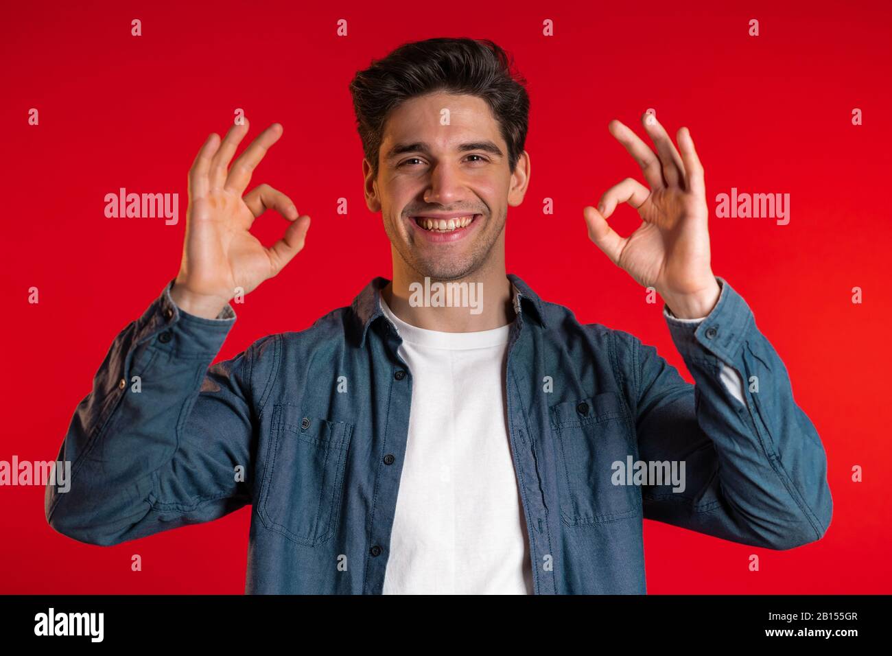 Young handsome man making OK sign over red background and smiles to ...