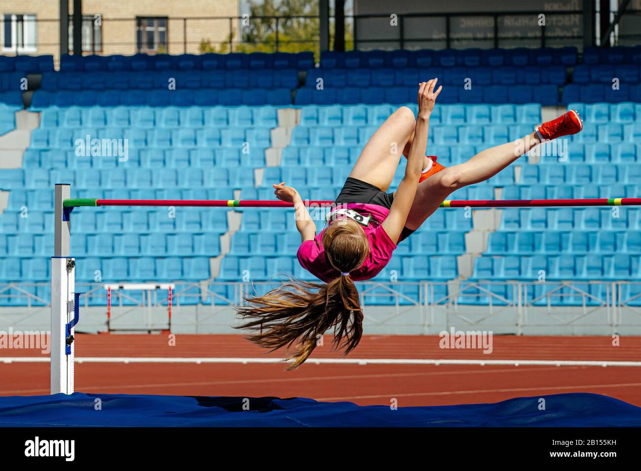 woman athlete jumper high jump at stadium on background of spectator ...