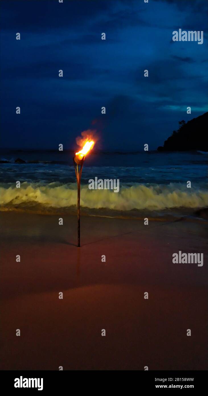 Burning torch on the sandy beach of the ocean Stock Photo - Alamy