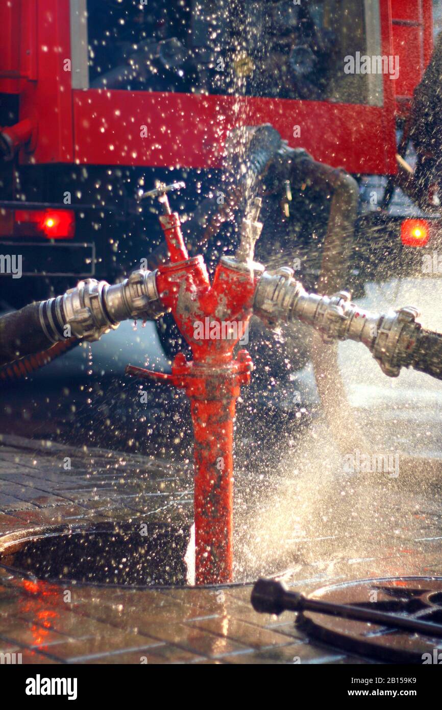 Water splashes from the fire hose and hydrant connections. Firefighters ...