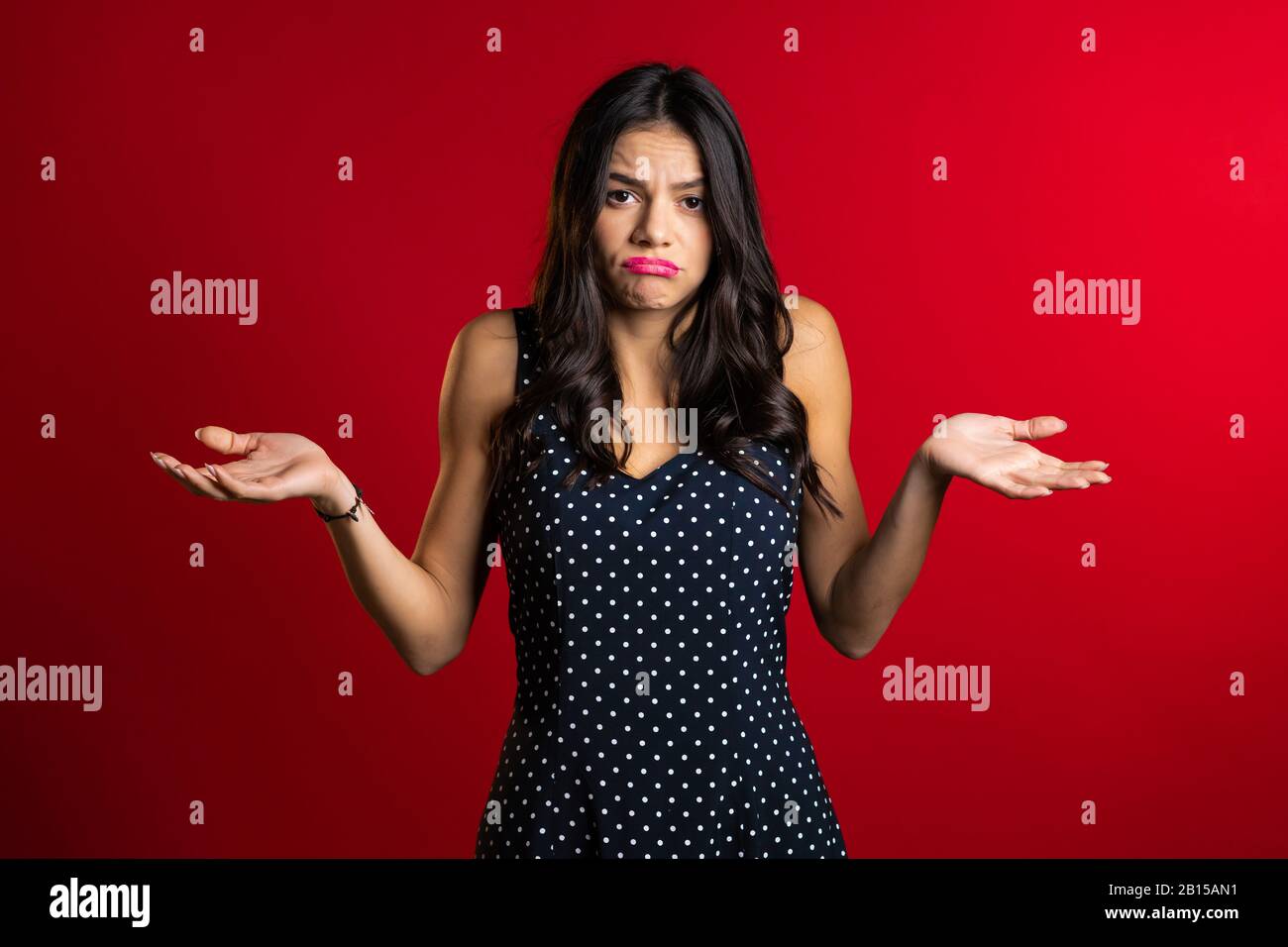 Young unsure girl shrugs her arms, makes gesture of I don't know, care ...