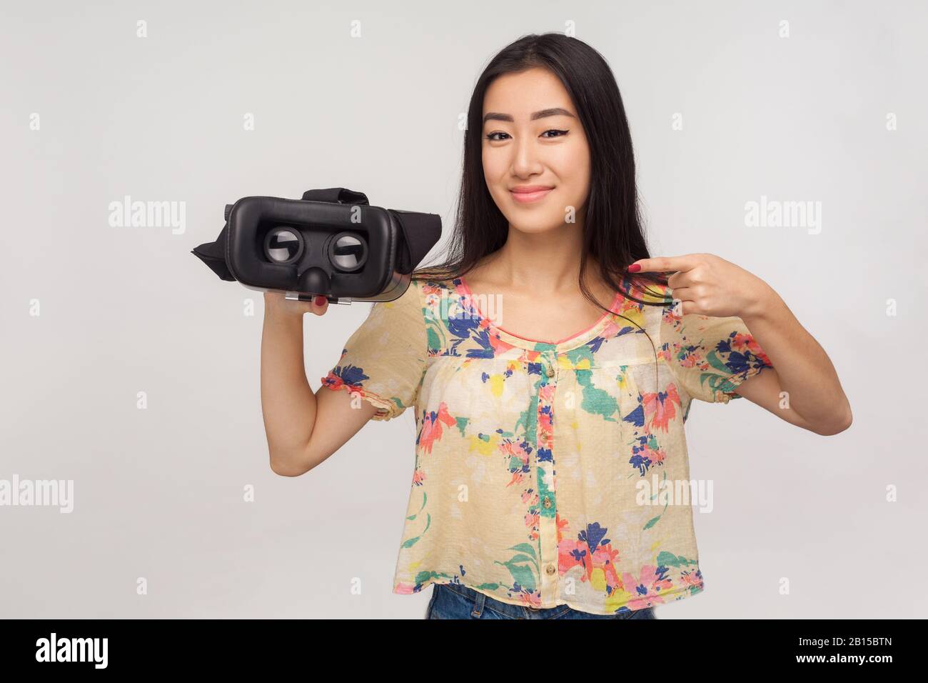 Positive Asian Girl Pointing Vr Glasses And Smiling At Camera Showing