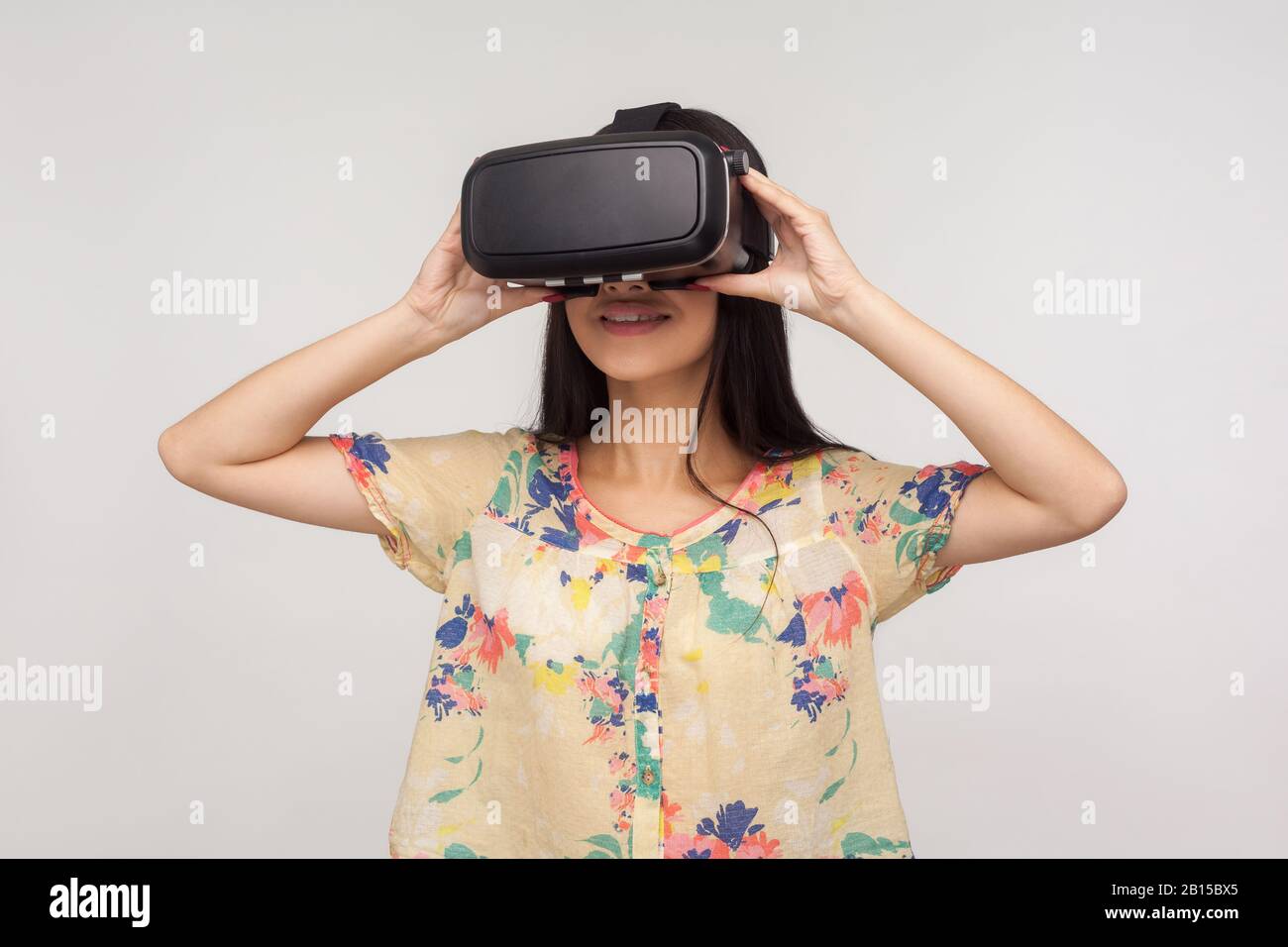 Happy young woman wearing VR glasses and watching virtual world with ...