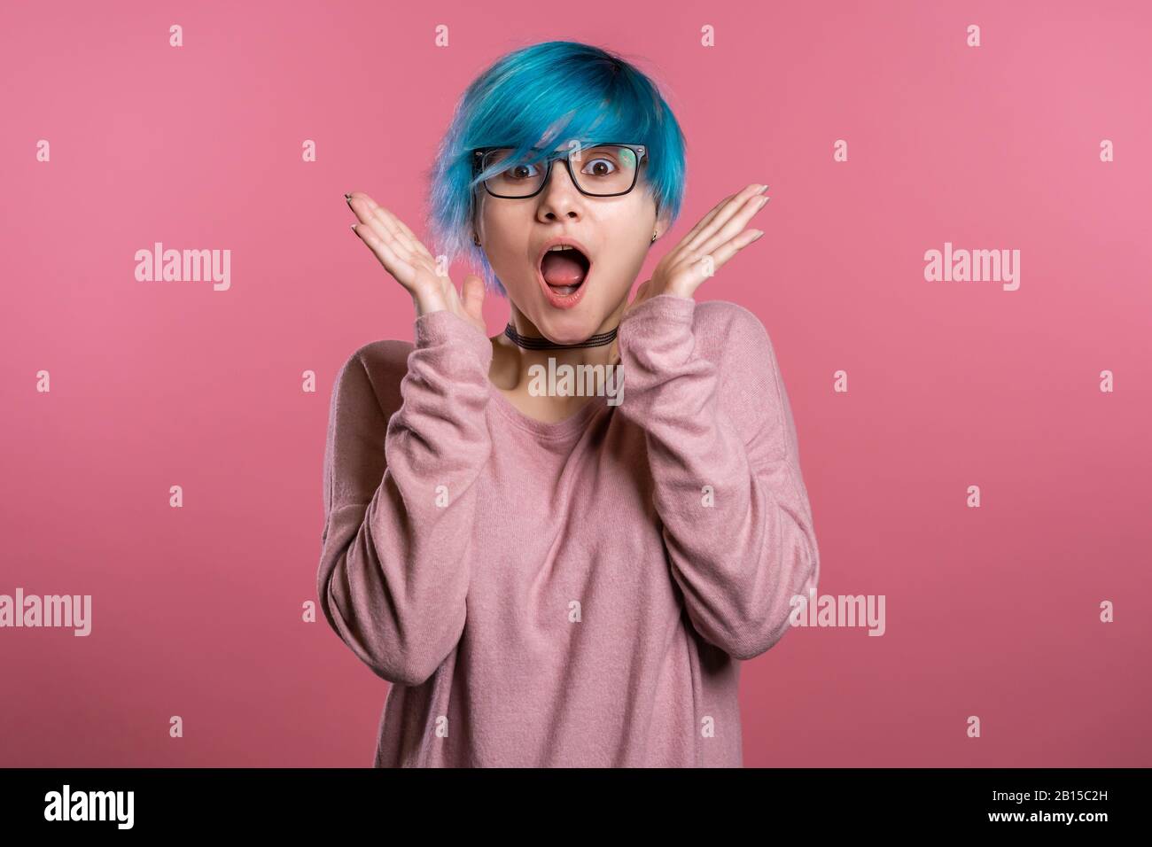 Pretty female shocked model with colorful hairstyle on pink background ...