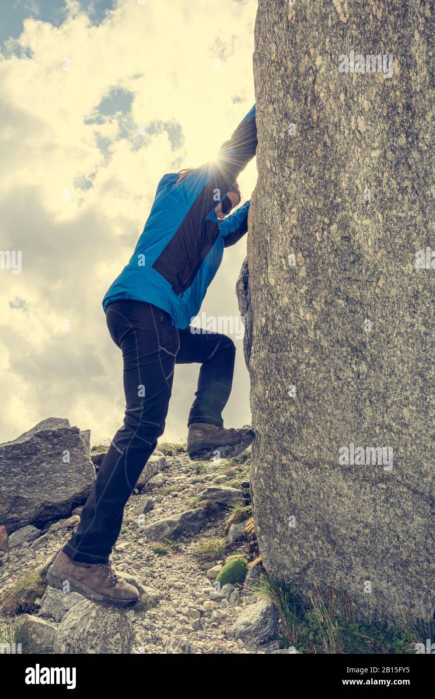 Female mountaineer practicing boulder climbing outdoor on large boulder ...