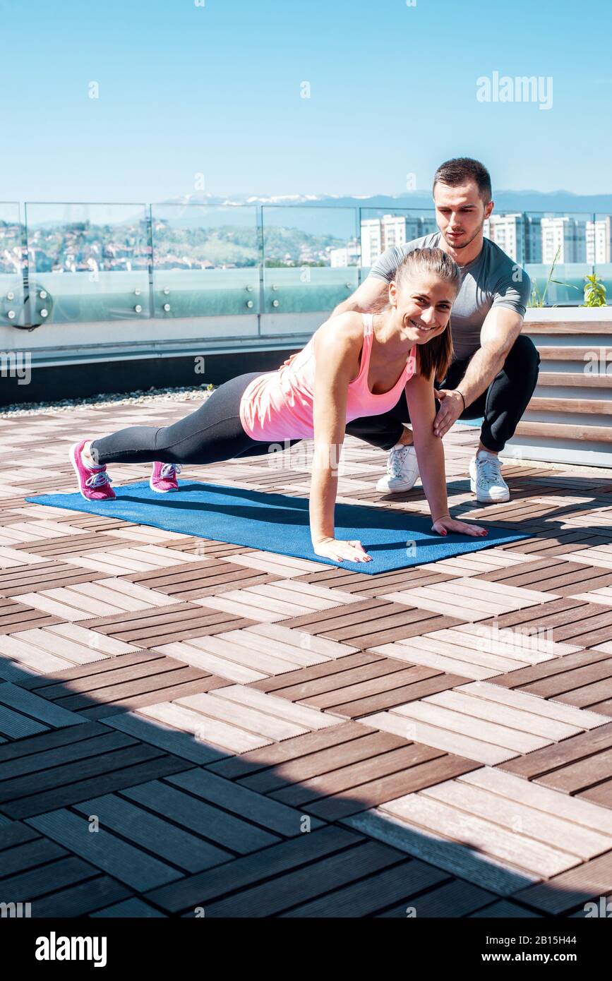 Personal trainer support and motivate his client while doing push ups ...