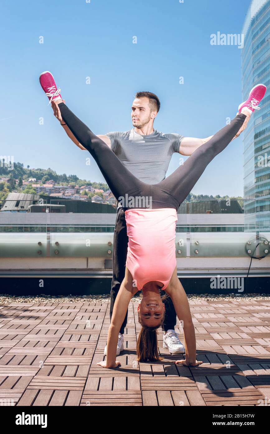 Female fitness woman doing handstand while her personal coach supports ...